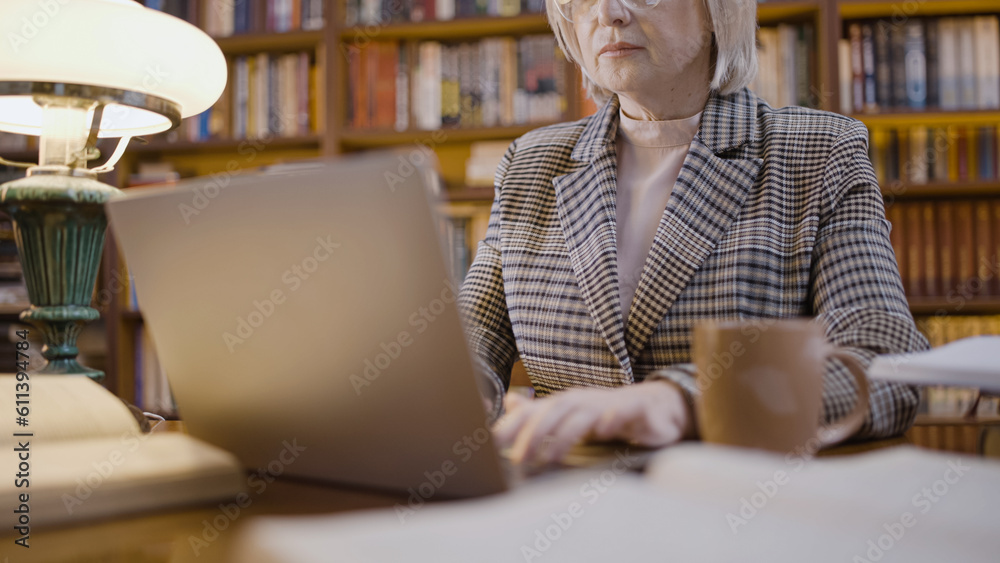 Overworked journalist writing a new article on her laptop, working late ...