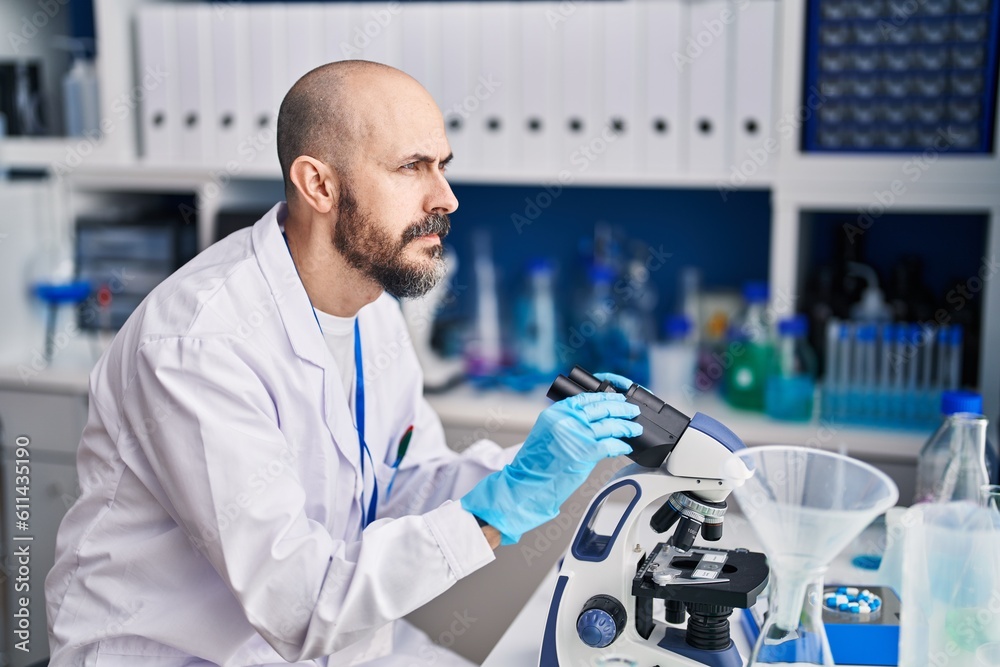 Young bald man scientist using microscope at laboratory Stock Photo ...