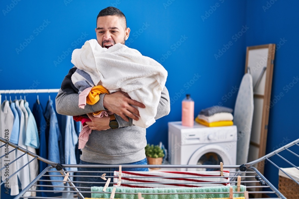 Hispanic man hanging clothes at clothesline angry and mad screaming ...