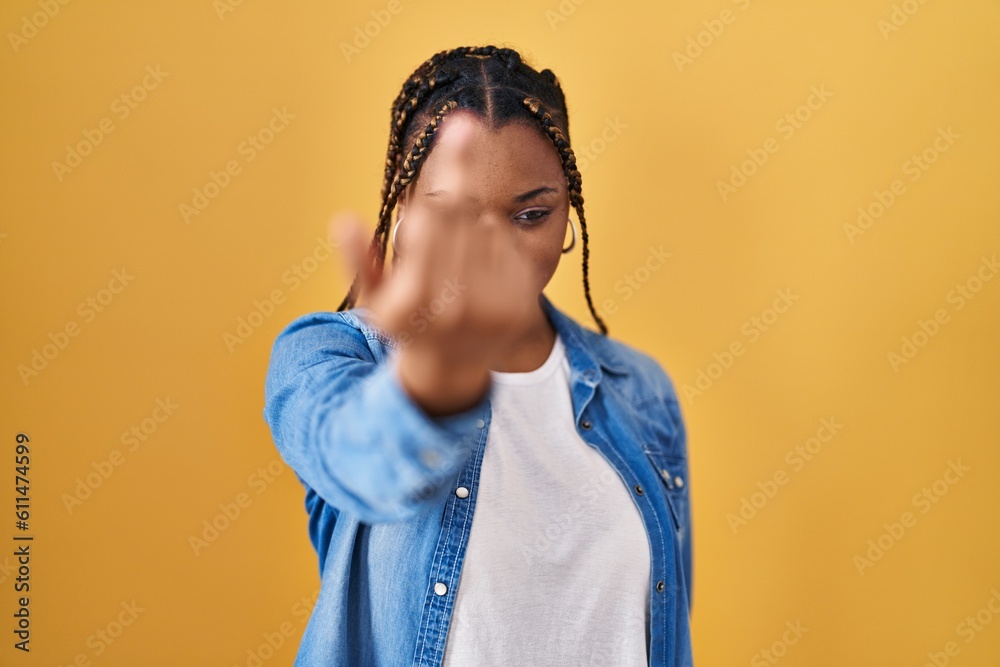 African american woman with braids standing over yellow background ...
