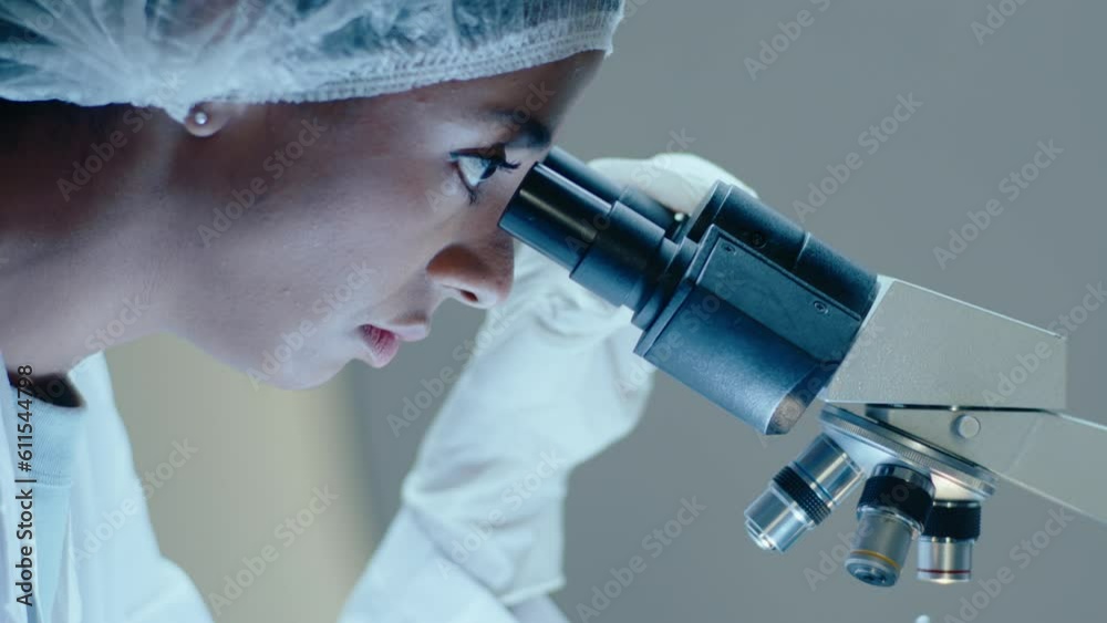 Female African-American scientist wearing white coat, medical hat and ...