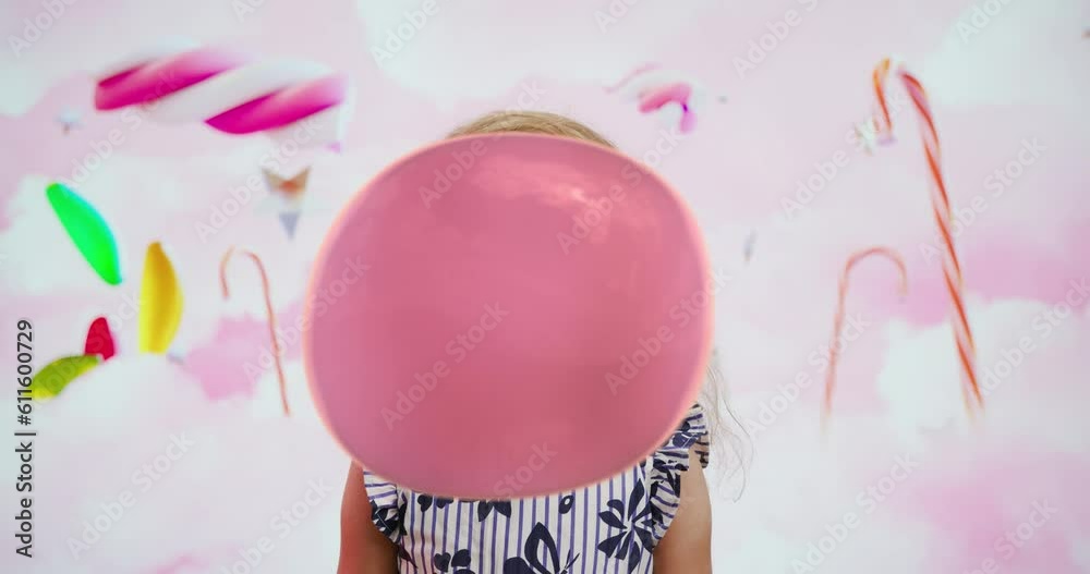 The small girl in the world of candies and sweets blowing a big bubble from bubble gum. Small ...