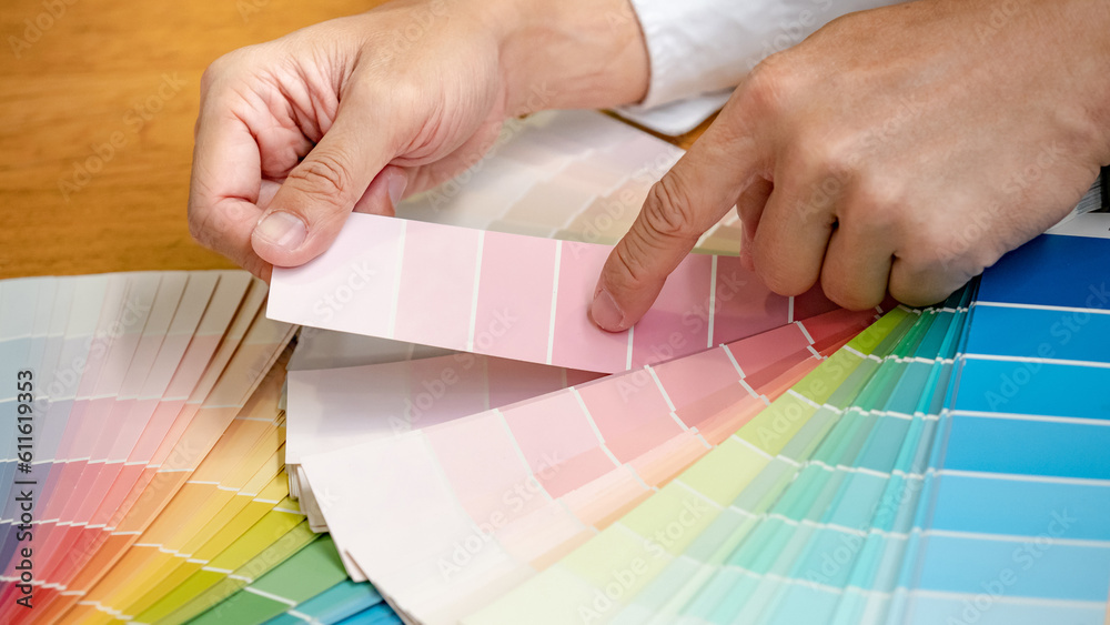 Designer hand choosing and pointing at color swatch samples catalog or ...