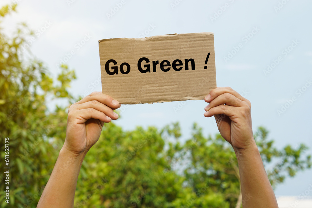 Foto de Hands hold paper sign with text Go Green! in forest. Concept ...