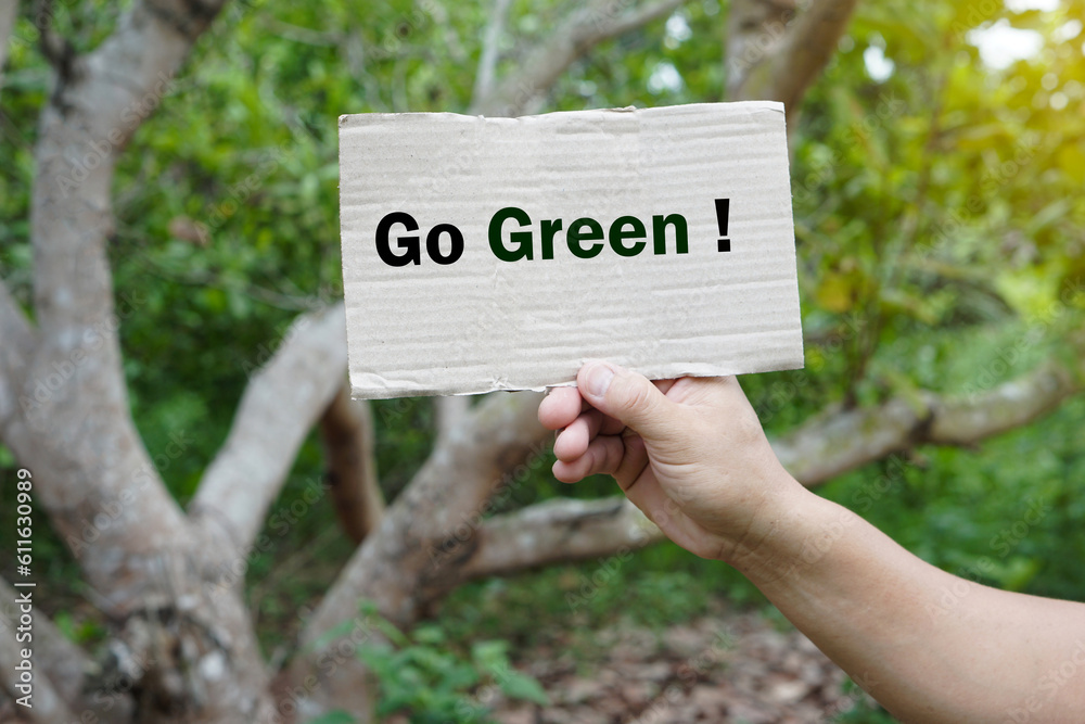 Foto de Hands hold paper sign with text Go Green! in forest. Concept ...