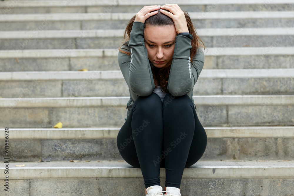 Disappointed and sad woman sitting on stairs. She sits alone and thinks ...