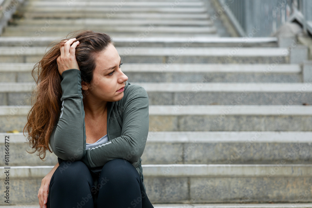 Disappointed and sad woman sitting on stairs. She sits alone and thinks ...