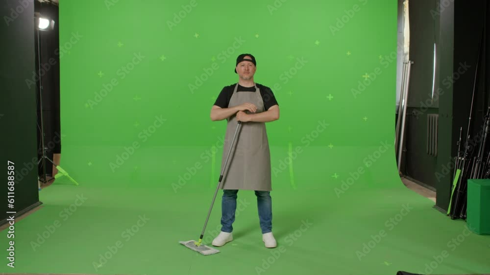 the waiter standing with a mop in his hands on green screen chroma key ...