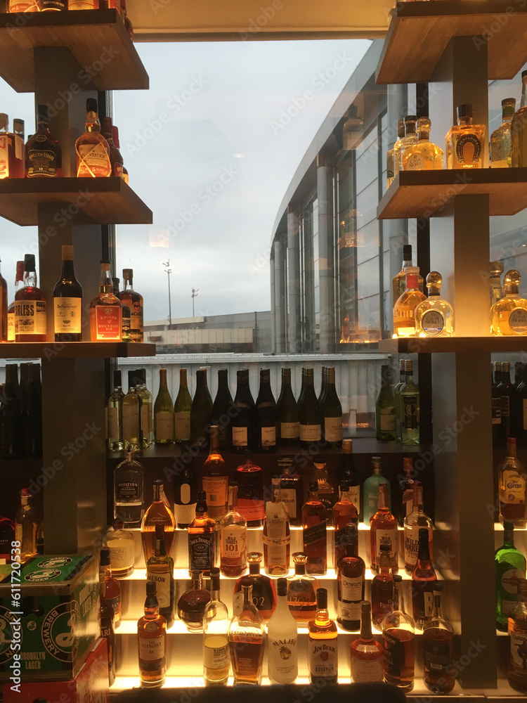 Liquor bottles on shelves lit from beneath at the airport bar at JFK ...