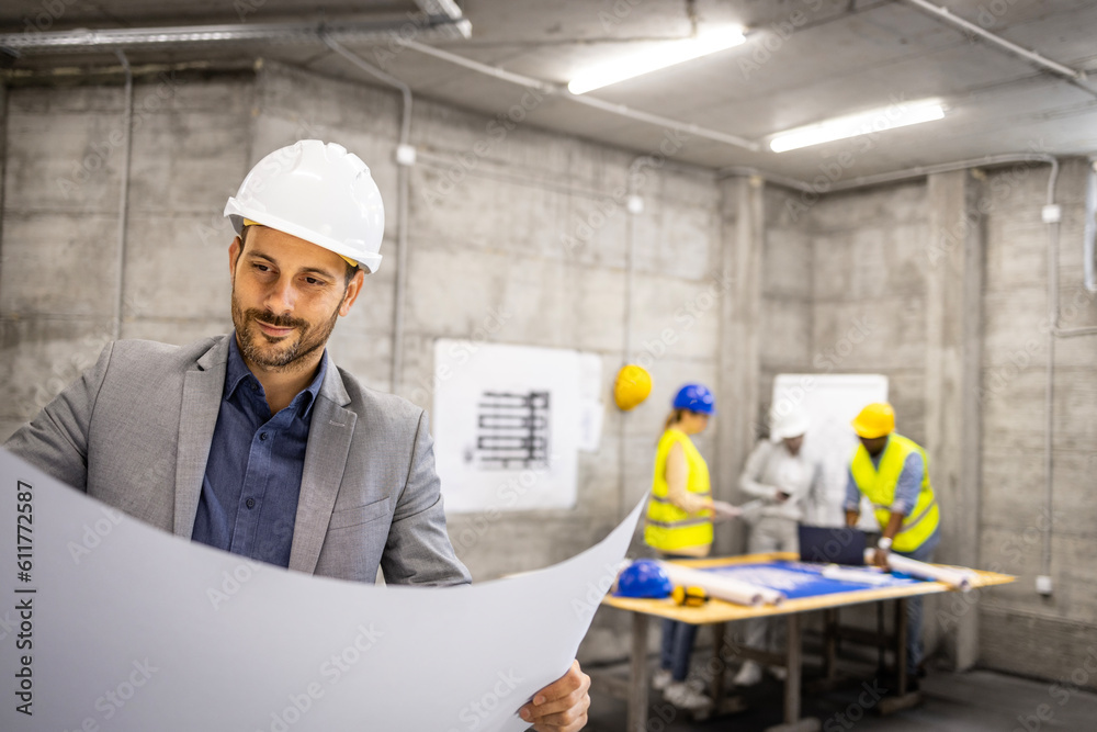 Contractor looking at building plans and blueprint at construction site ...