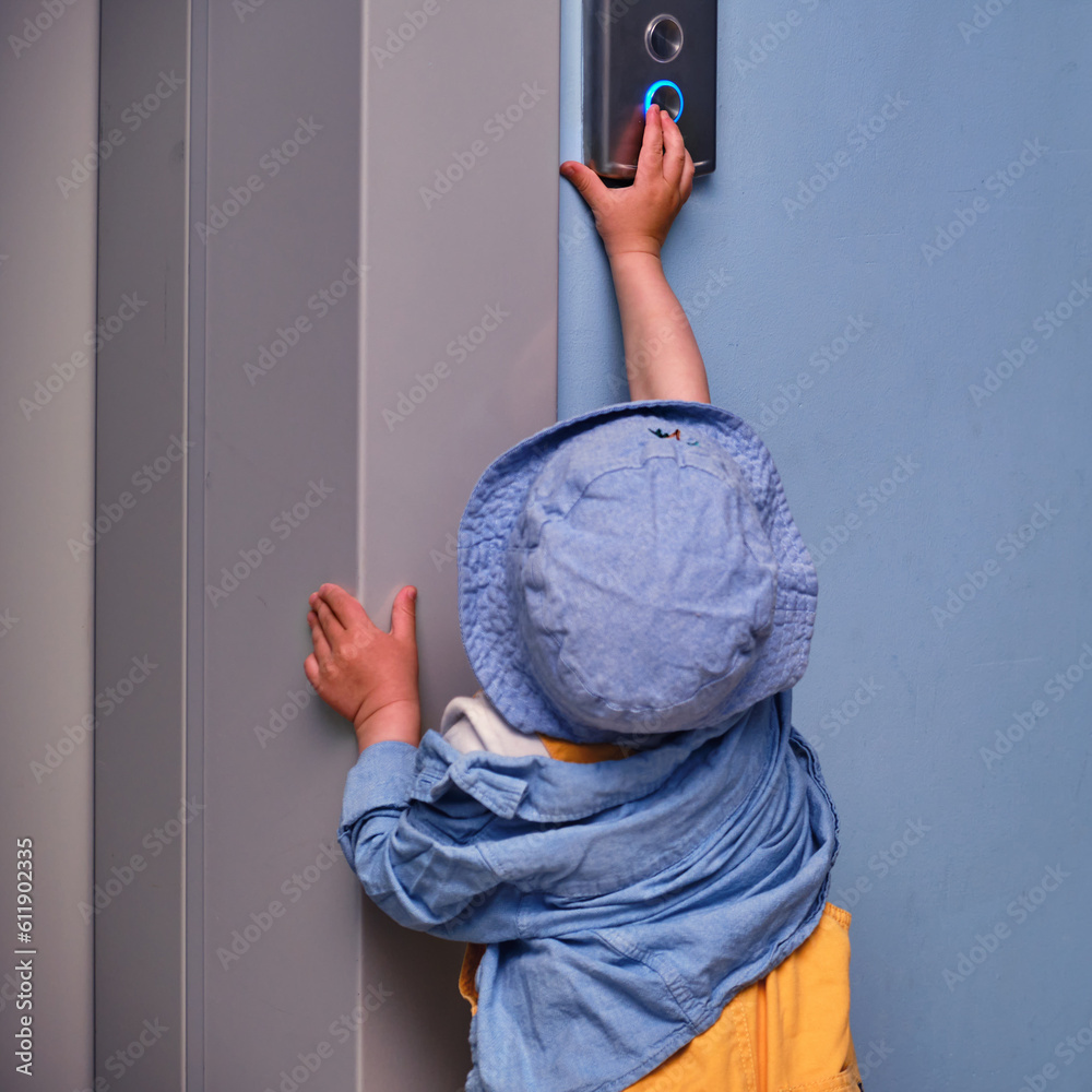 Toddler baby calls the elevator by pressing the button in the entrance ...