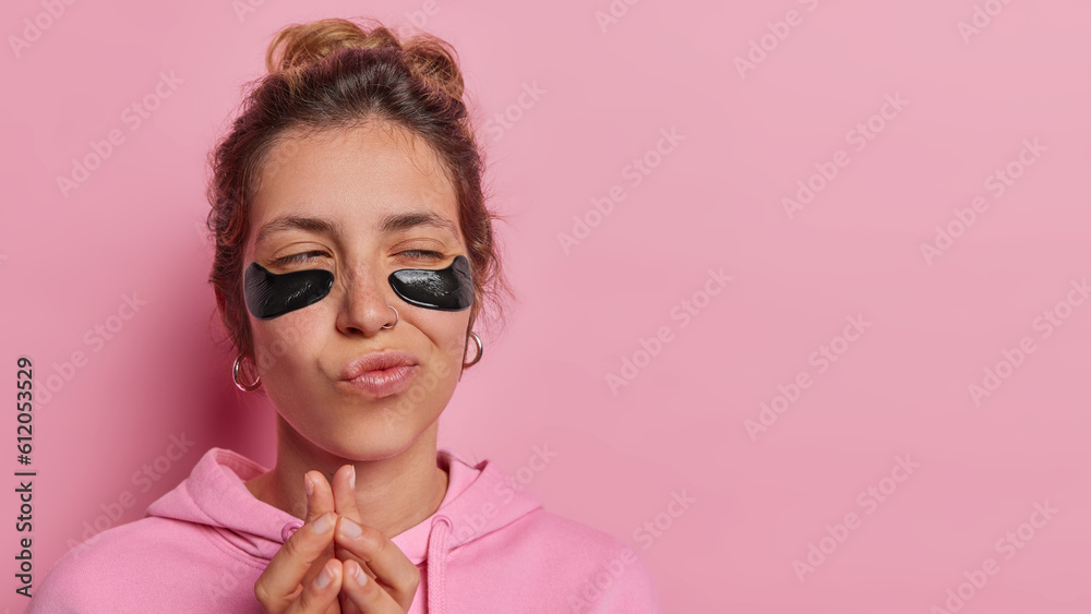 Horizontal shot of thoughtful young woman schemes something in mind ...