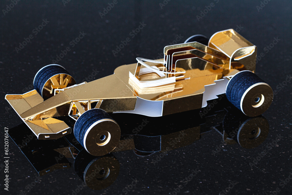 A Formula 1 racecar made out of golden and black cardboard and placed ...