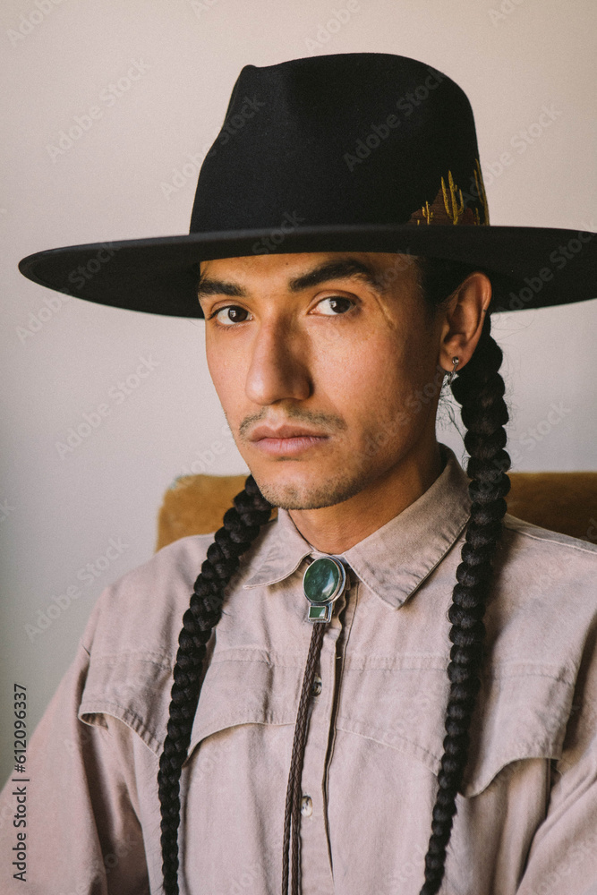 Portrait of Mexican native Indian queer man with braids and bolo tie ...
