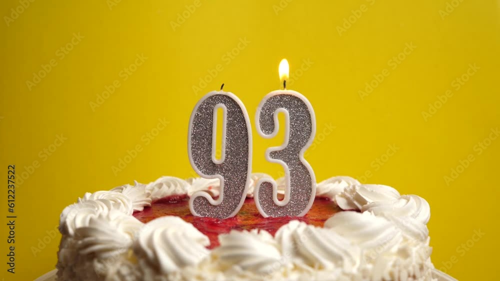 A candle in the form of the number 93, stuck in a holiday cake, is ...