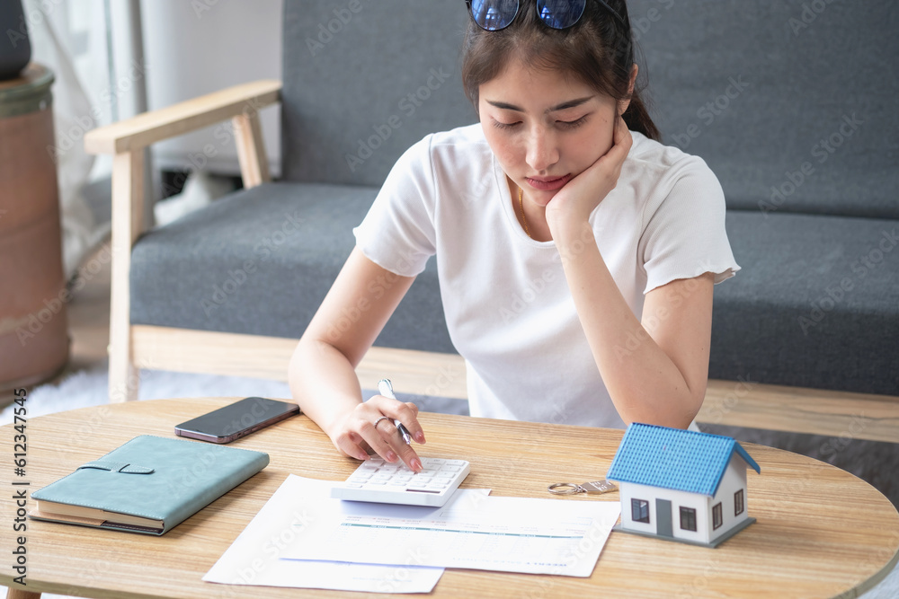 Young Asian woman sitting and calculating expenses and mortgage with ...