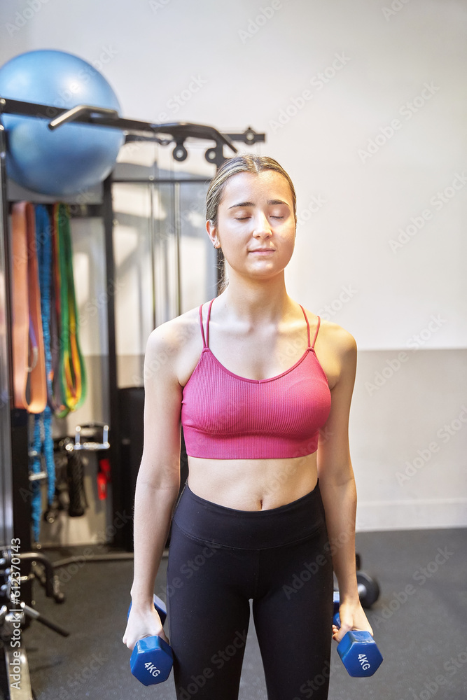 Blonde Girl's Dynamic Arm Exercises with Dumbbells at the Gym for ...