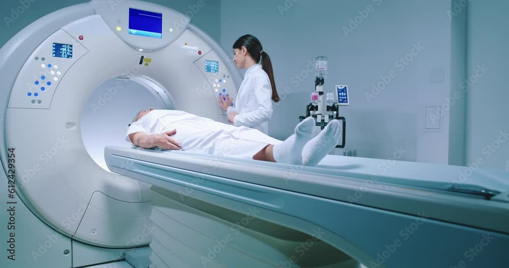 Medical worker adjusts capsule of MRI examination. Patient lies on MRI ...