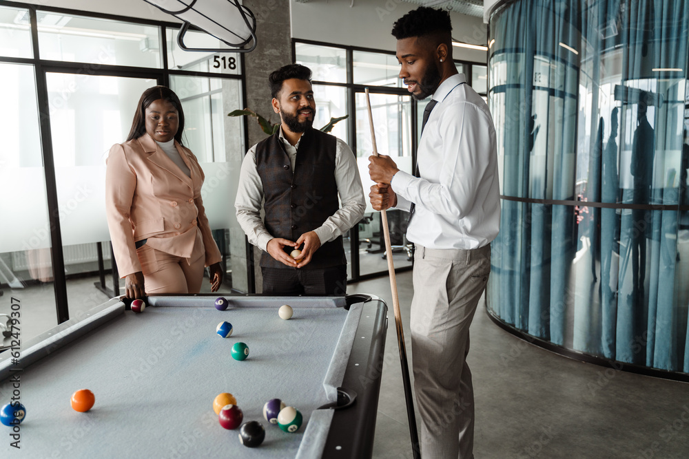 Young multiracial people in suits playing pool at office lobby Stock ...
