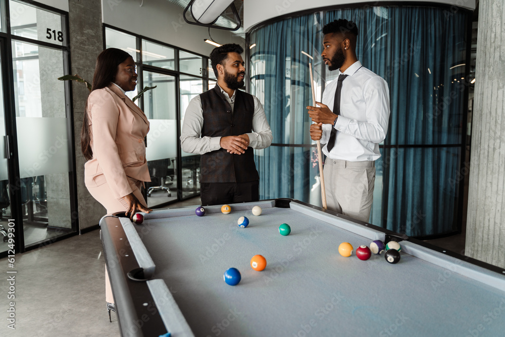 Young multiracial people in suits playing pool at office lobby Stock ...