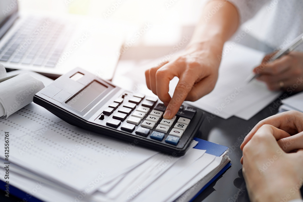 Woman accountant using a calculator and laptop computer while counting ...