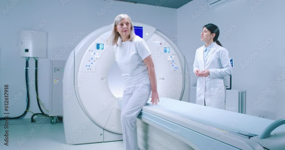 Middle-aged woman is going to MRI capsule. Female doctor is welcoming ...