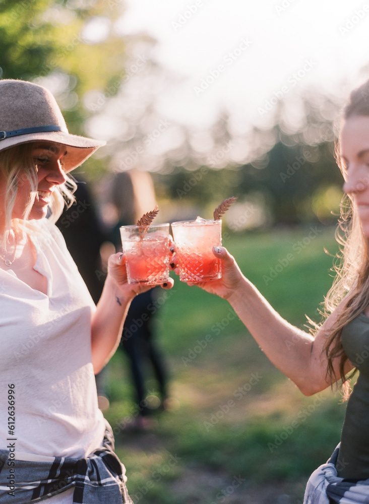 two women cheers their cocktails together at an outdoor event Stock ...