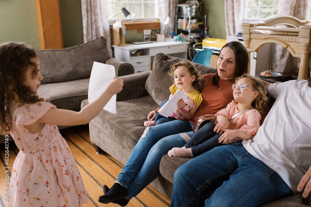 little girl showing her family a picture she drew Stock Photo | Adobe Stock
