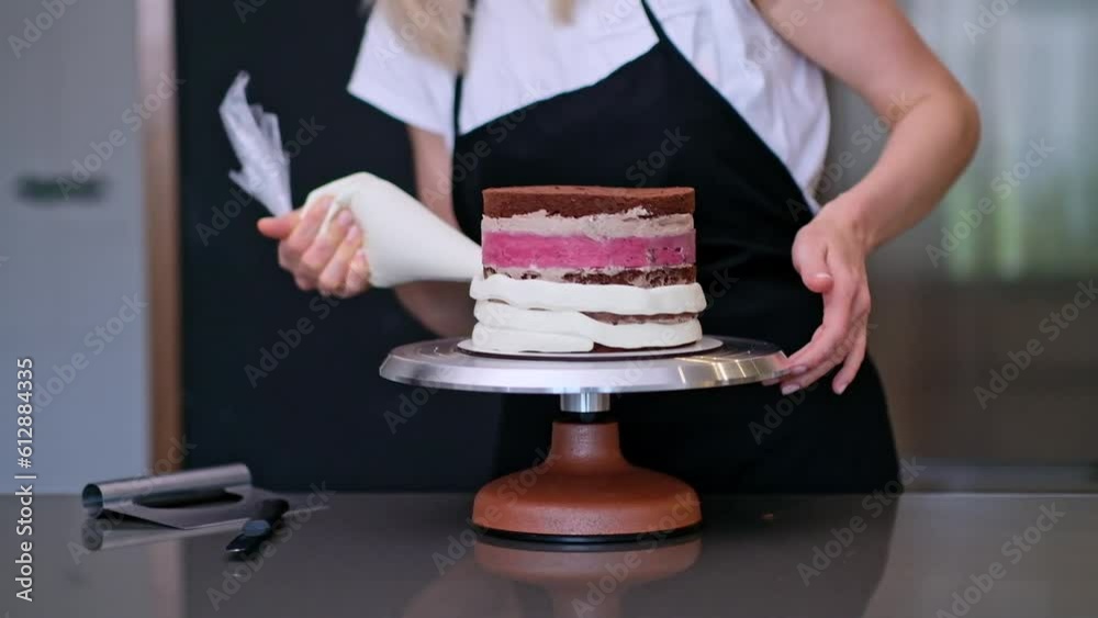 Skilled woman putting sweet white mastic around baked cake using pastry ...