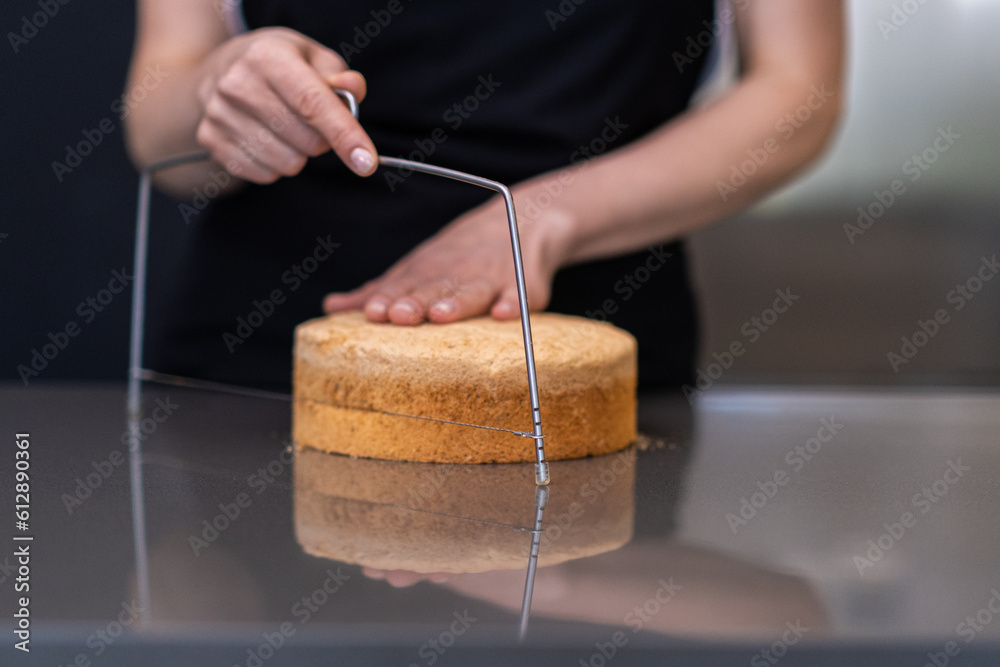 Professional confectioner in black apron putting hand on cake cutting ...