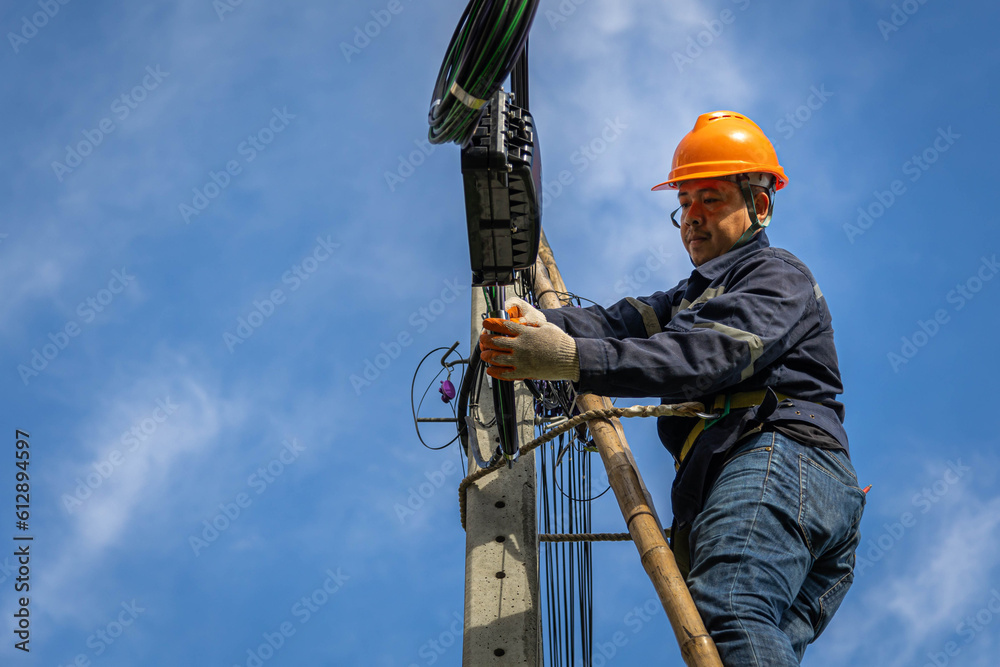 A technician working on ladder carefully for maintenance fiber optic ...