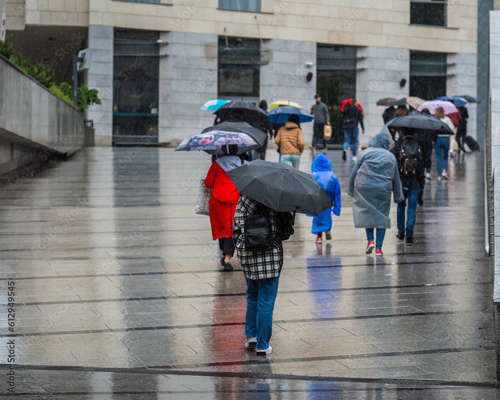 Authentic passers-by with and without umbrellas, with raincoats, walk ...