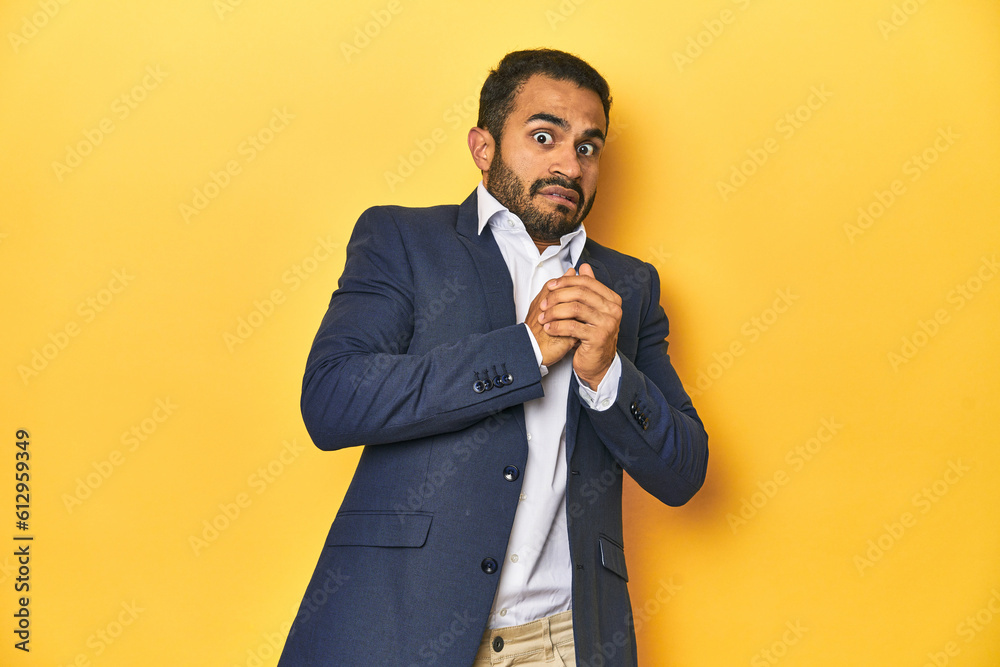 Professional young Latino man in business suit, yellow studio ...