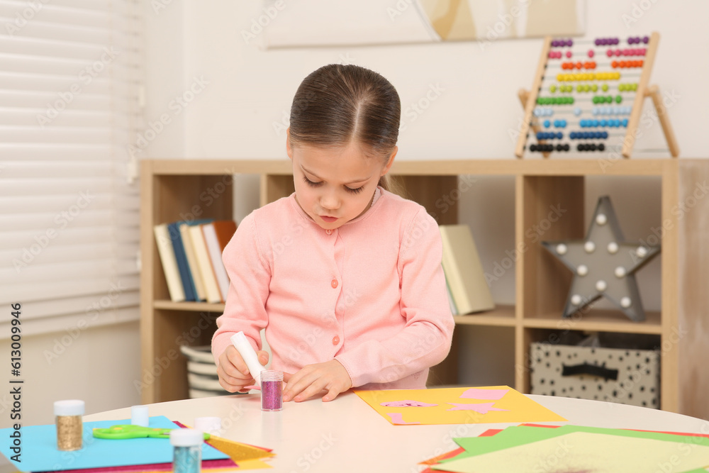 Cute little girl using glue stick at desk in room. Home workplace Stock ...