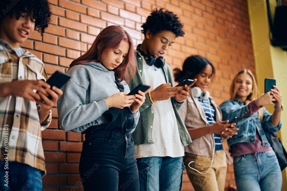 Multiracial group of teenagers using their cell phones at high school ...