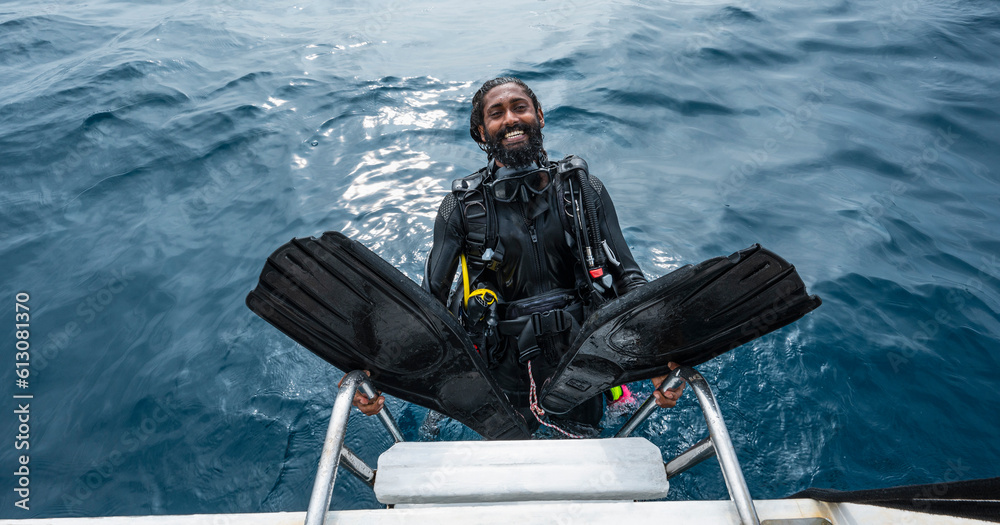 diver climbing up to a boat after finishing a dive in the Maldives ...