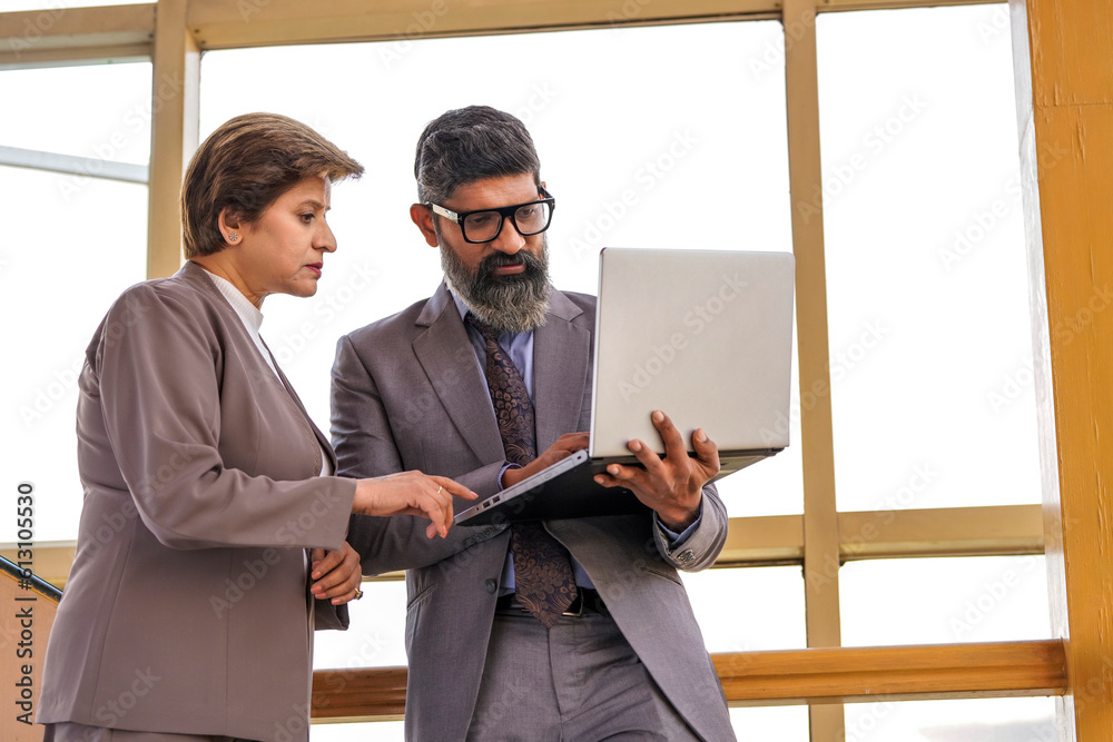 Indian businessman showing some detail to secretary in laptop, boss and ...