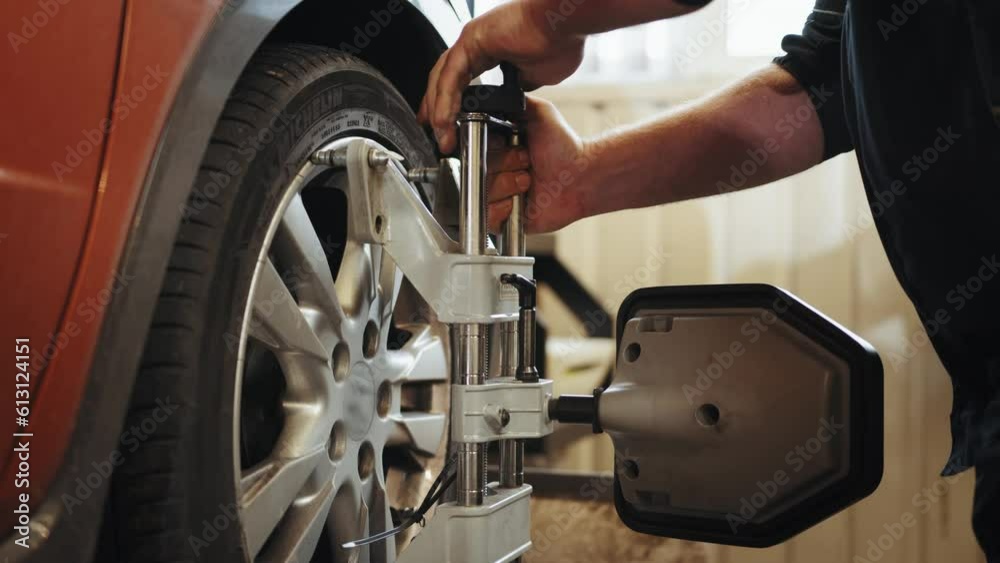 A car service employee installs a wheel adapter with a target on the ...