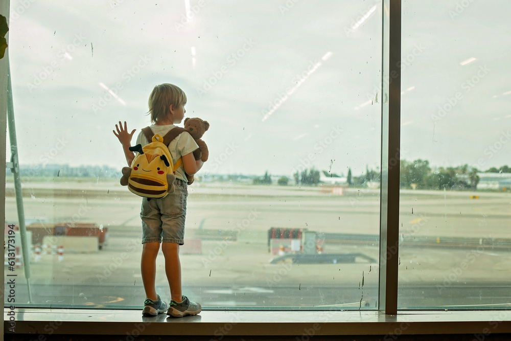 Child, watching from the window of the airport the planes, taking off ...