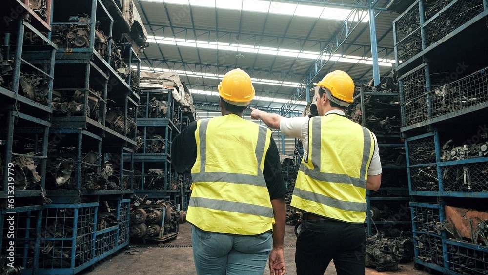 Back view of two warehouse workers in safety uniform walking and ...