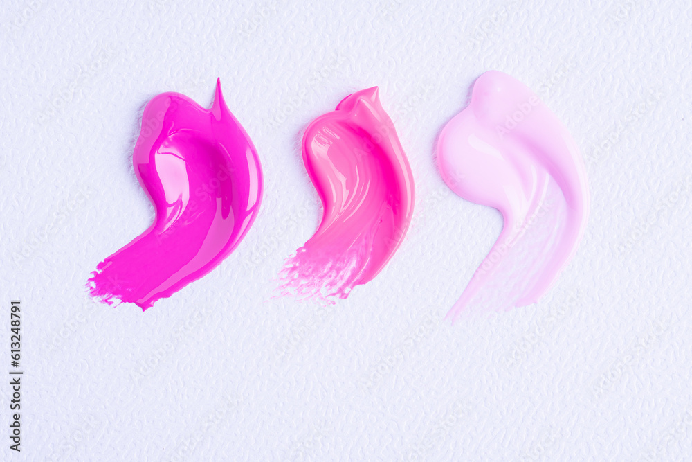 Three smears of different pink paint swatch on white paper background ...