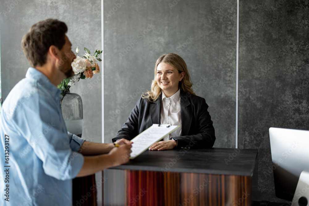 Foto de Young medical receptionist talks with a male client and gives ...