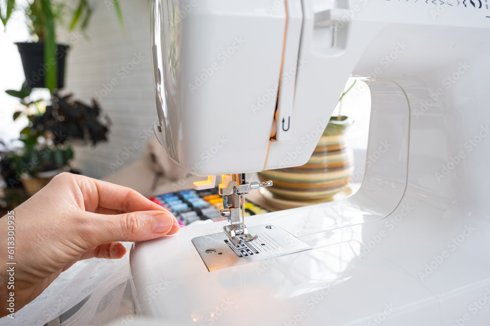 Woman hand close up sews tulle on electric sewing machine. Filling the ...