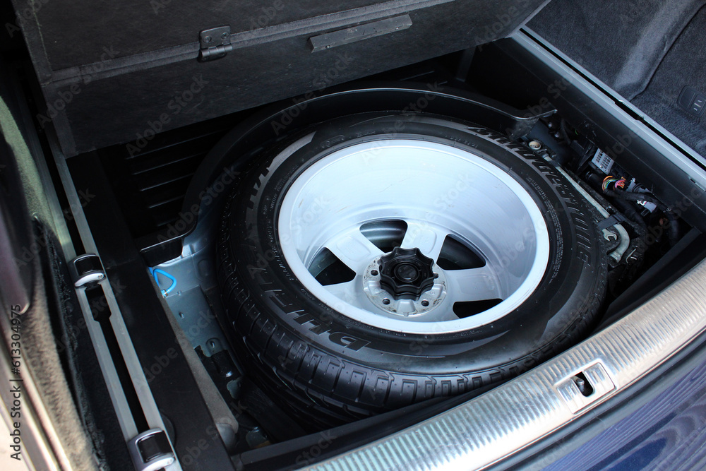 Spare wheel in the trunk of a modern car. Jack lifting and a spare tire ...
