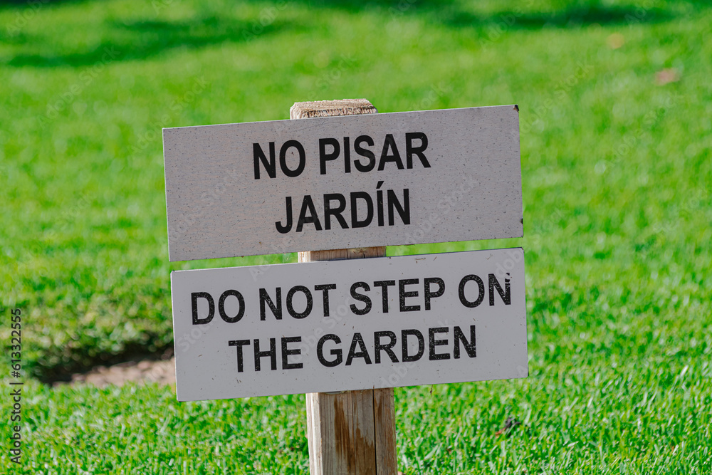Do no step on the garden sign, in english and spanish, with green grass ...