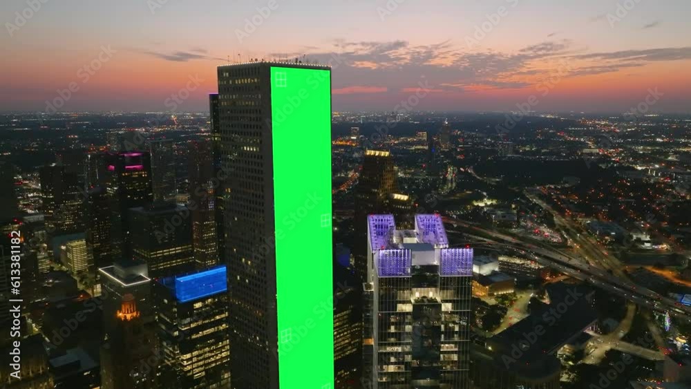 Green screen banner tracked on a skyscraper wall, dusk city background ...