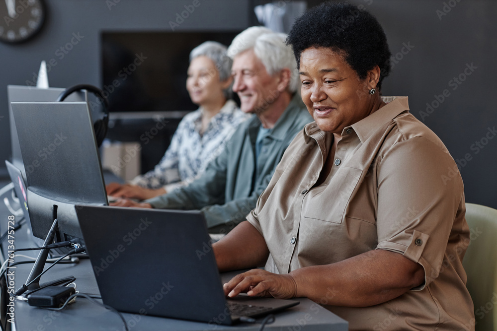 Portrait of senior black woman using computer and smiling in computer ...