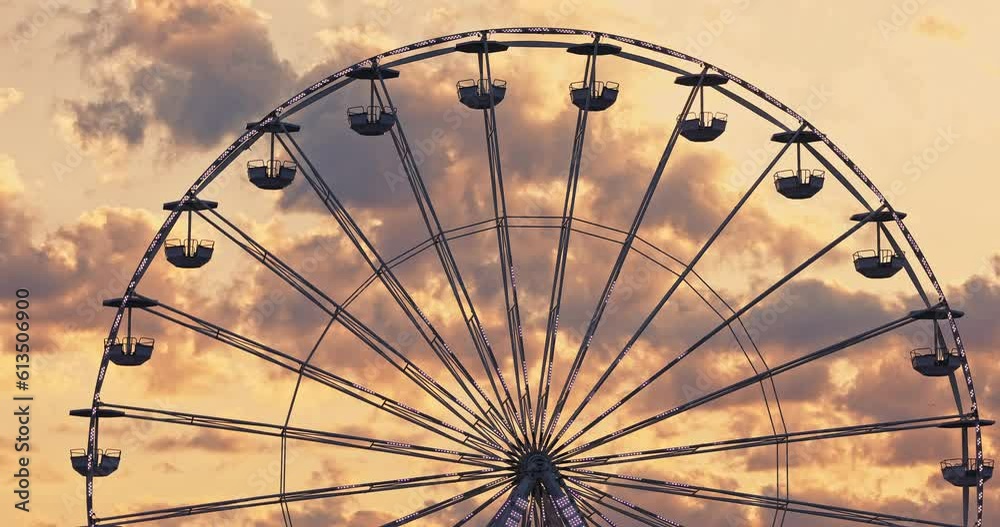 Spinning Ferris Wheel in amusement park and scenic sunset clouds in sky ...