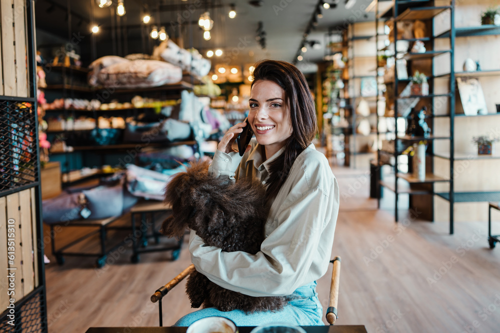 Foto de Beautiful and happy young woman sitting in modern pet shop cafe ...