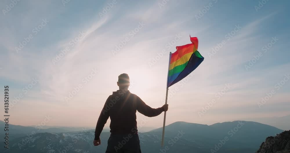 Rainbow LGBT flag. Man holding the rainbow waving flag standing on the ...
